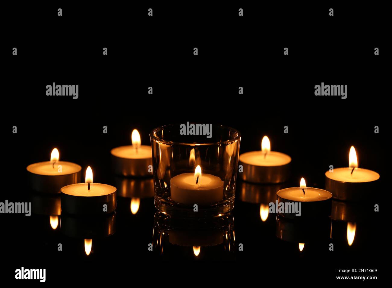 Burning small wax candles in darkness. Funeral symbol Stock Photo - Alamy