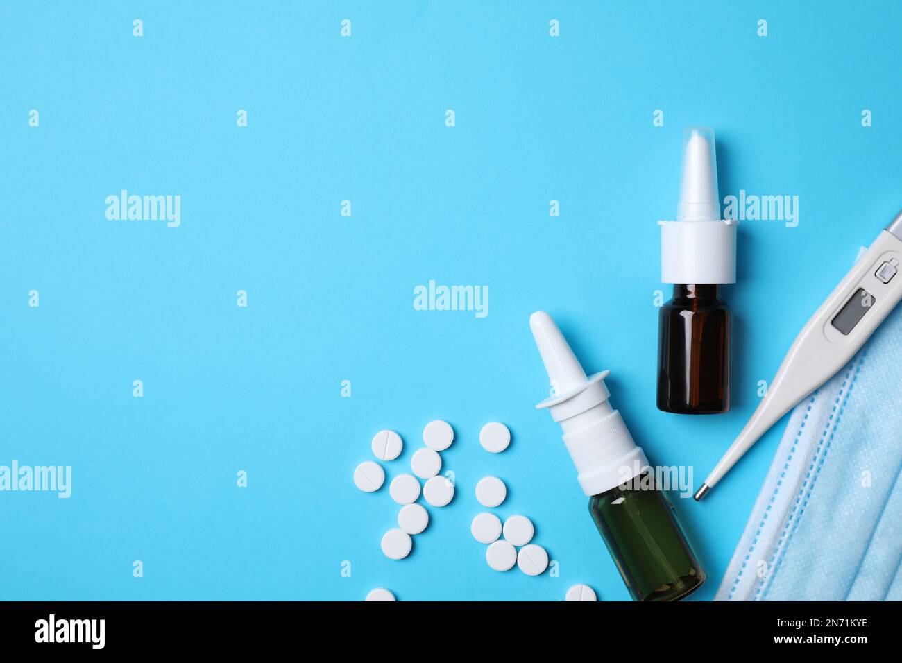 Thermometer, medicaments and respiratory mask on light blue background ...