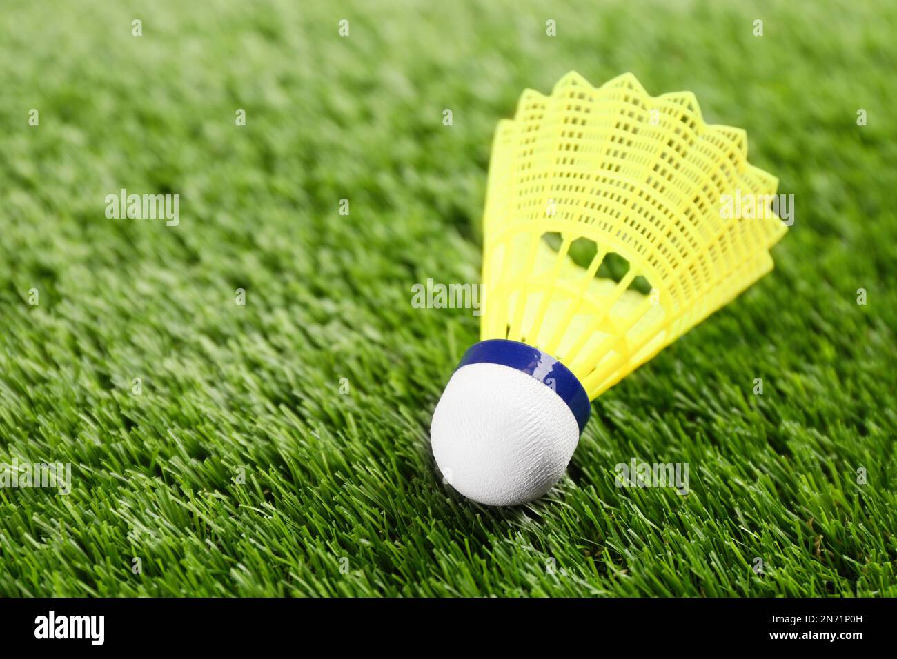 Badminton shuttlecock on green grass outdoors, closeup. Space for text ...