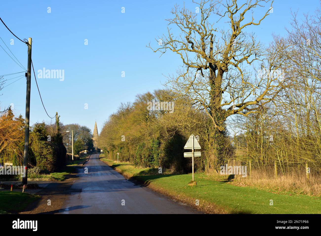 Local road leading to a small English village under a clear blue sky ...