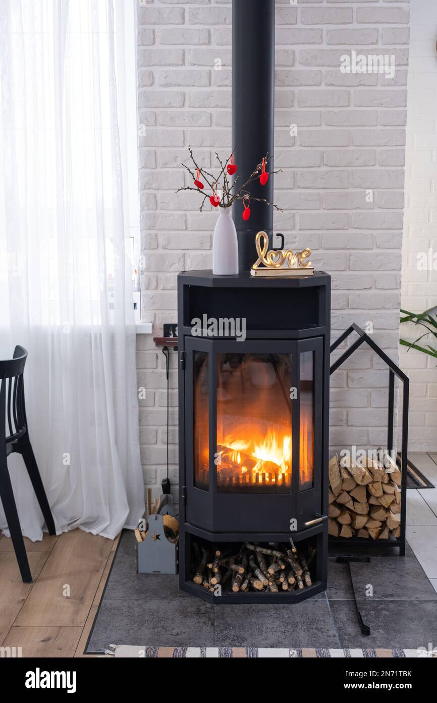 Valentine decor near fireplace stove with fire and firewood. Cozy home ...
