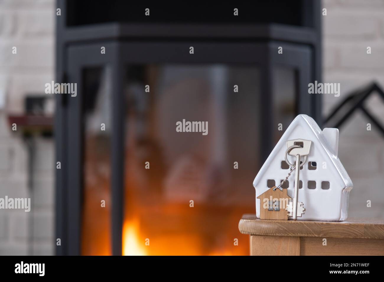 Key to house with keychain against background of fireplace stove with ...