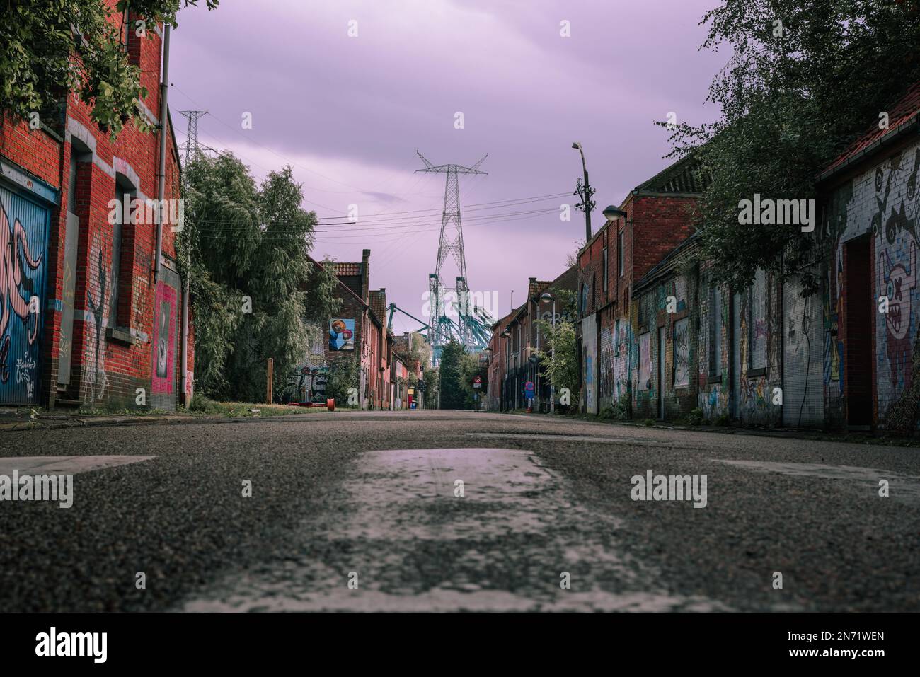 An overgrown abandoned street with old graffiti buildings in Doel ...