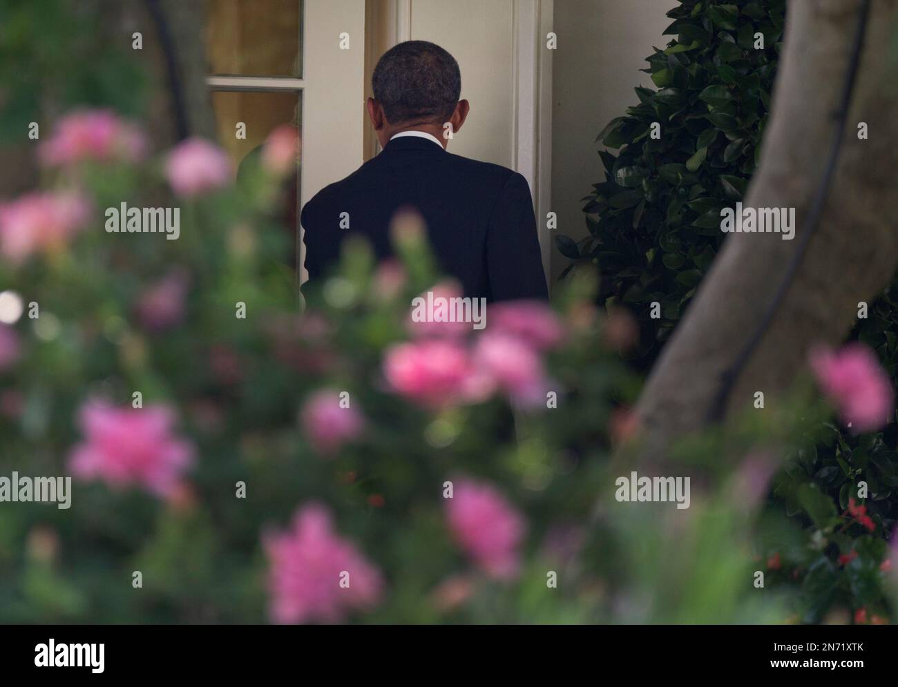 President Barack Obama opens the door and enters the Oval Office of the ...