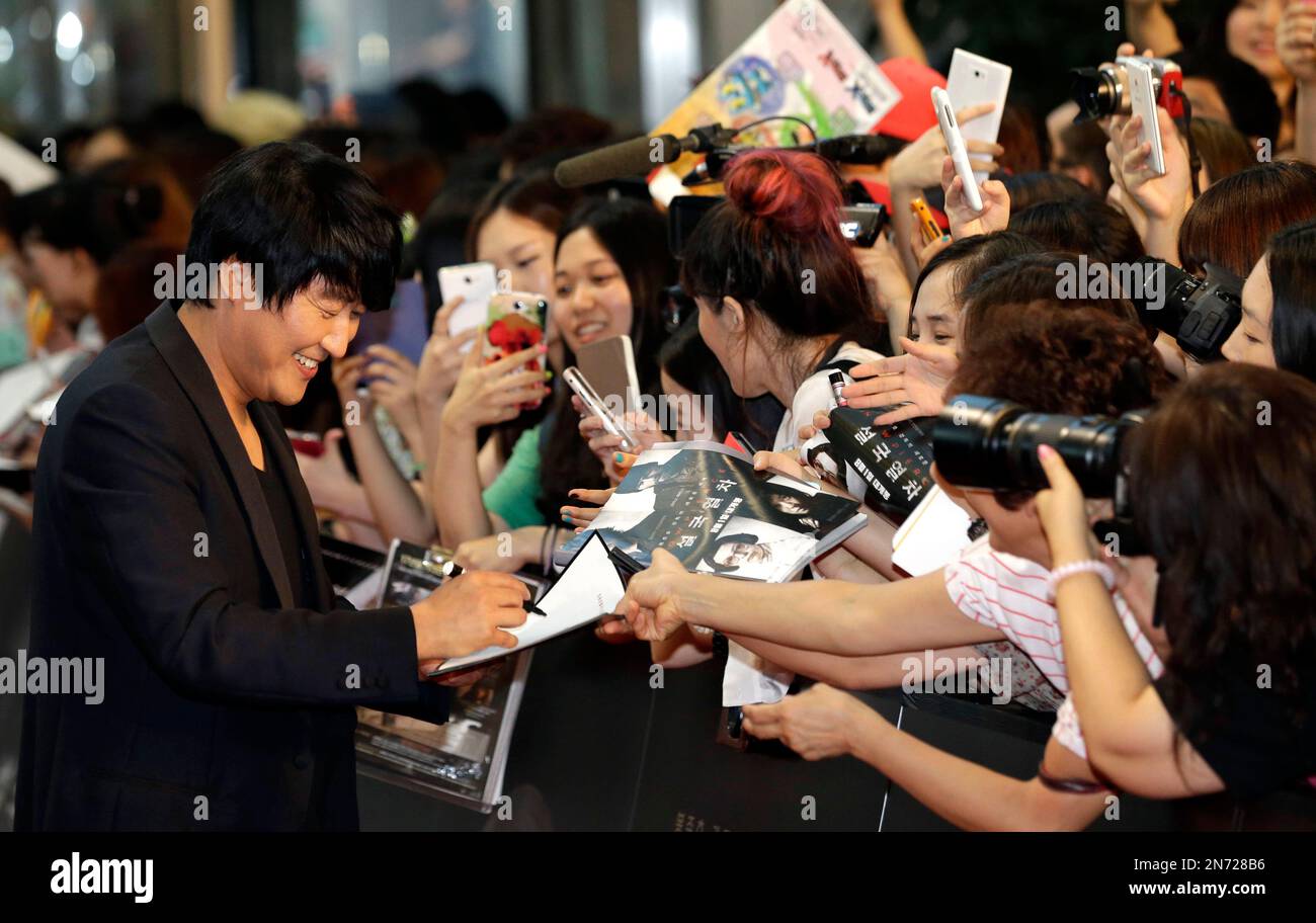 South Korean actor Song Kang-ho, left, signs his autograph for a fan ...