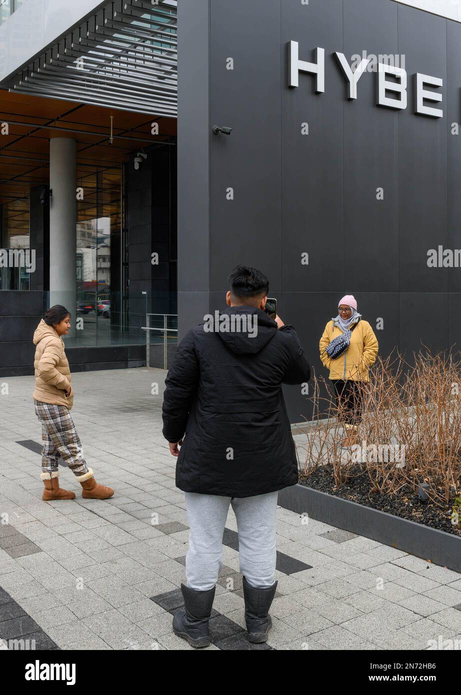People pose for a photo outside the Hybe headquarters building in Seoul ...