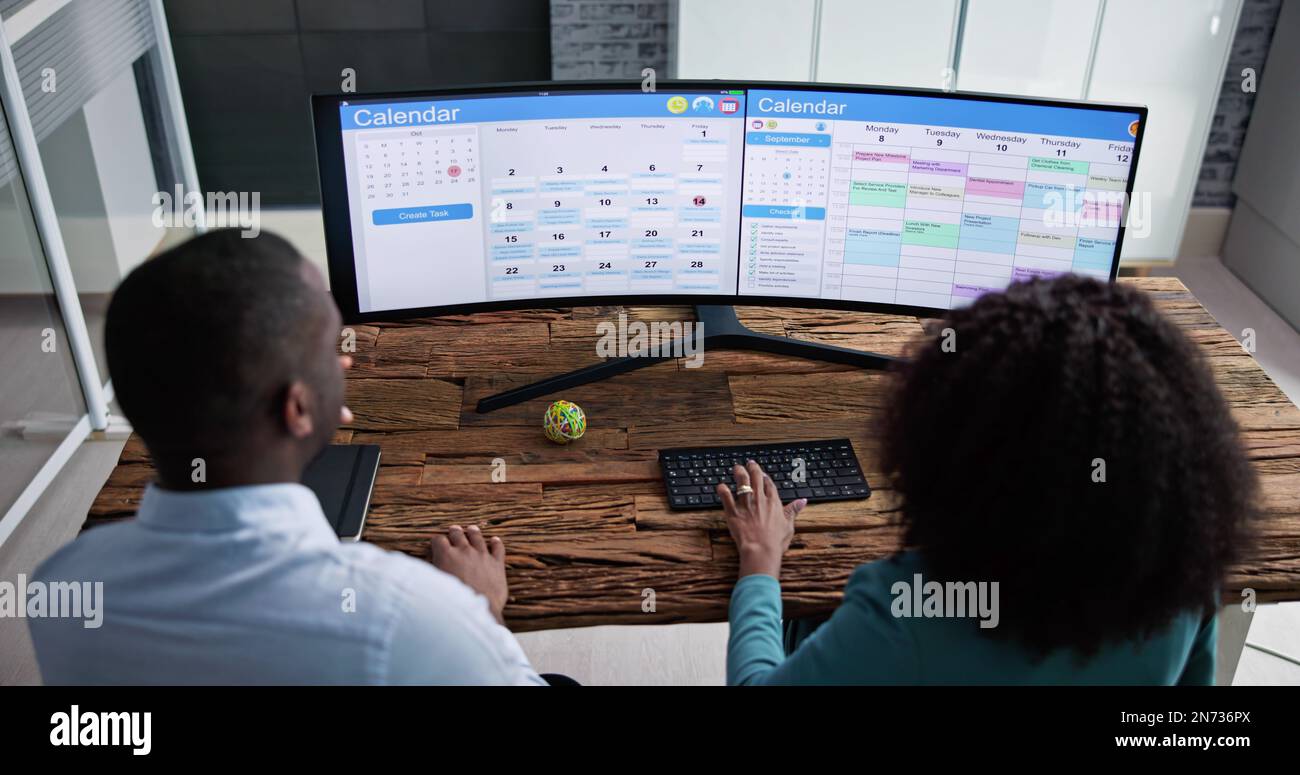 Young Businesspeople Analyzing Gantt Chart And Calendar On Computer In ...