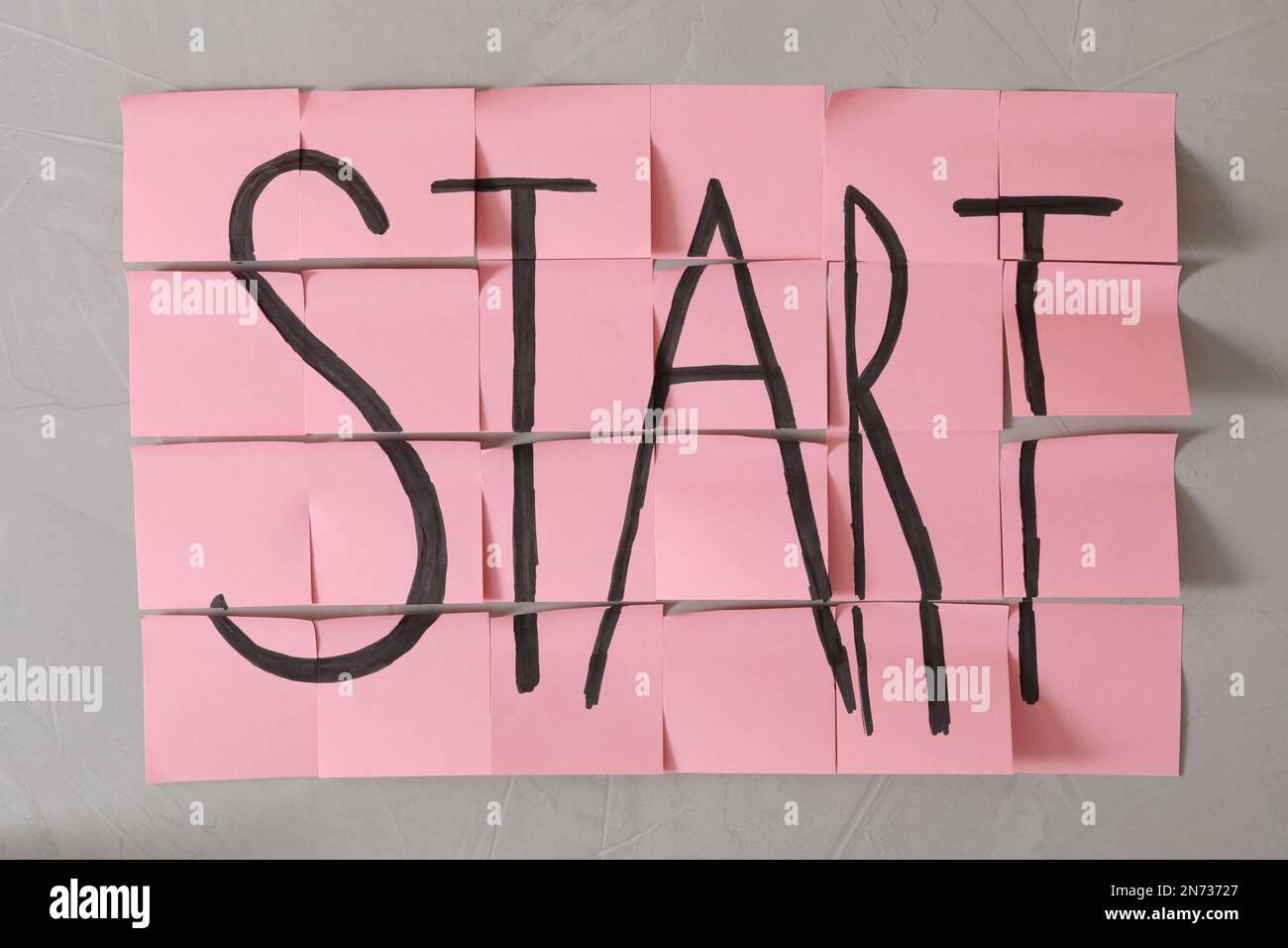 Pink sticky notes with word Start on light grey stone background, flat ...