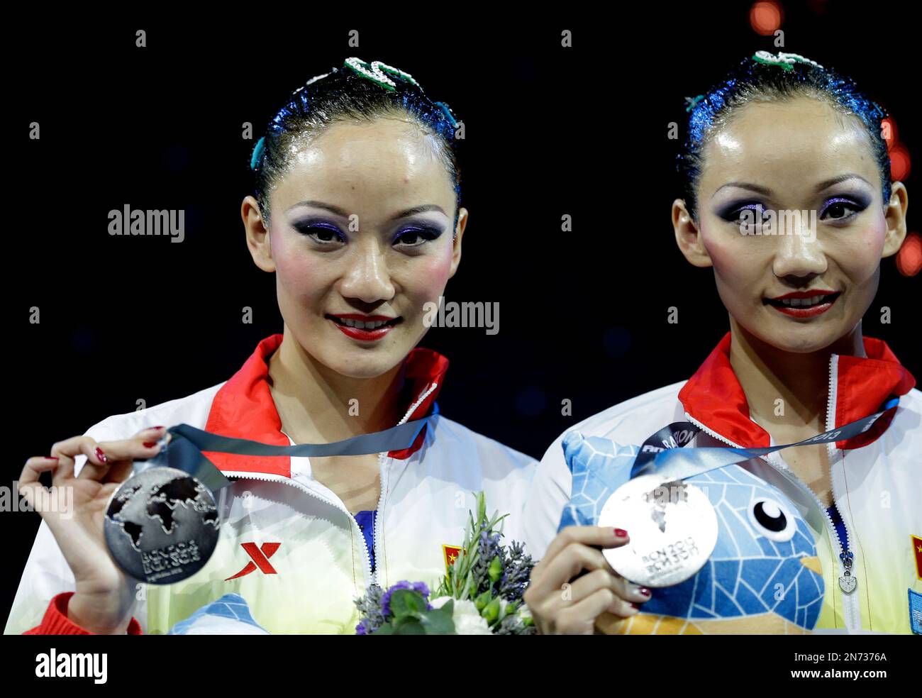 China's Jiang Tingting and Jiang Wenwen hold up their silver medals after the synchronized ...