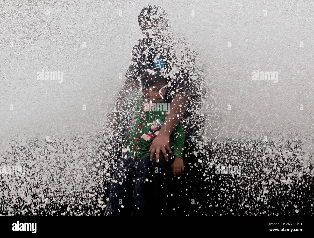 An Indian man holds his son as they enjoy along the Arabian Sea ...