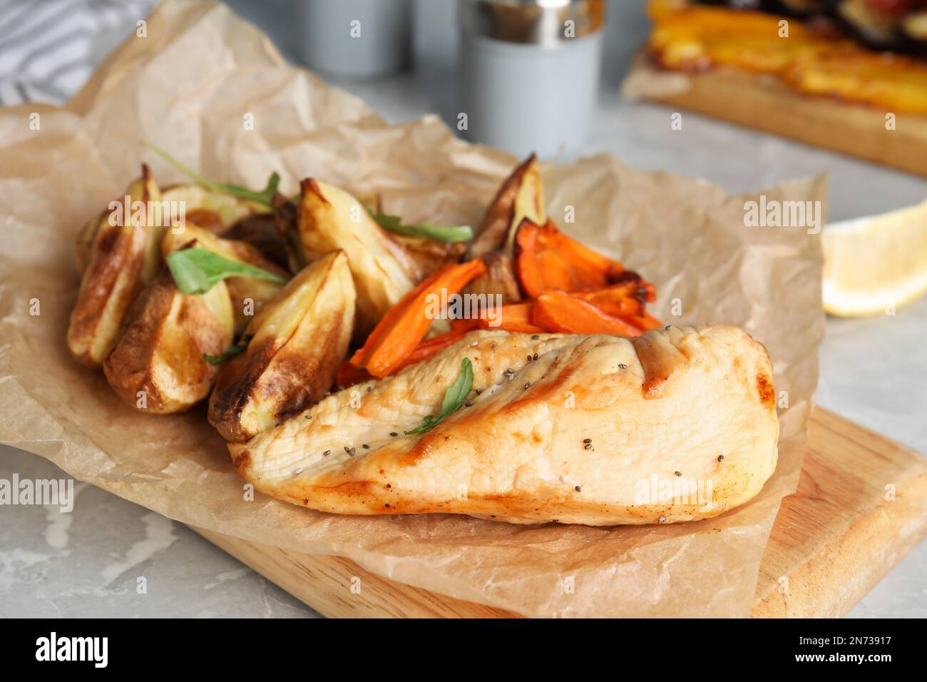 Delicious cooked chicken and vegetables on grey marble table, closeup ...