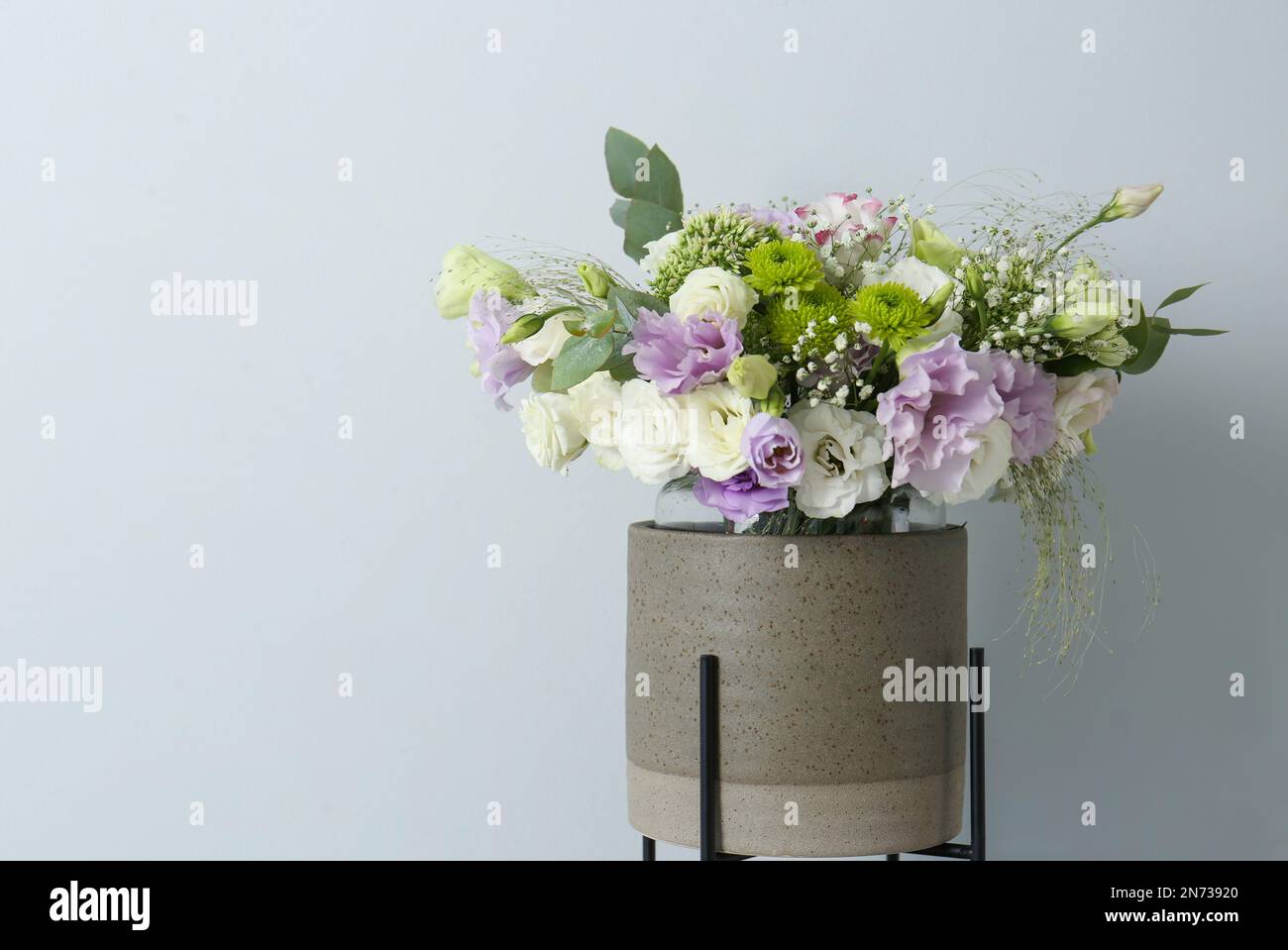 Bouquet with beautiful Eustoma flowers in ceramic cachepot on light ...