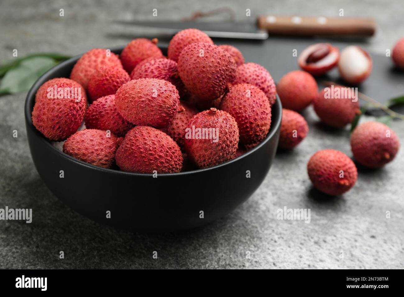 Fresh ripe lychee fruits in black ceramic bowl on grey table Stock ...