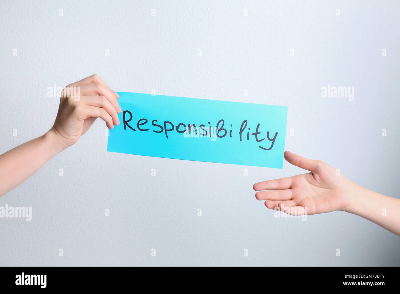 Woman giving light blue paper sheet with word Responsibility to ...