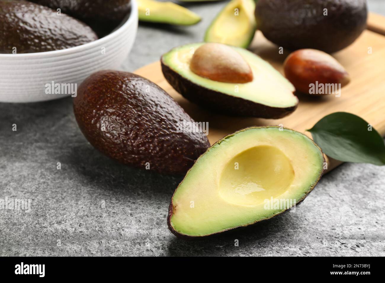 Whole and cut avocados on grey table, closeup Stock Photo - Alamy