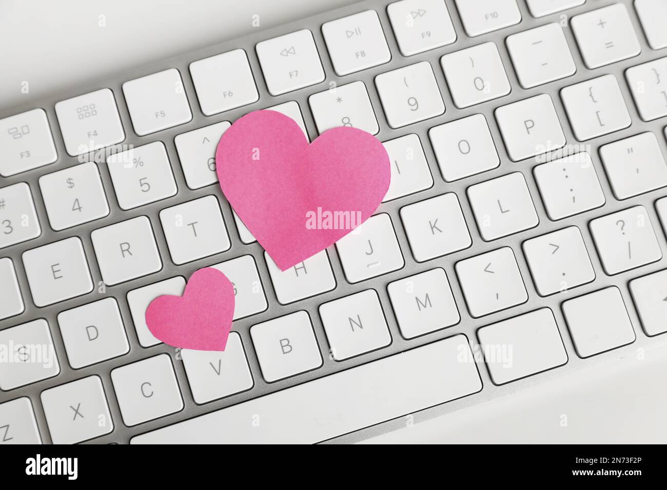 Keyboard with pink hearts on white table, top view. Valentine's day ...