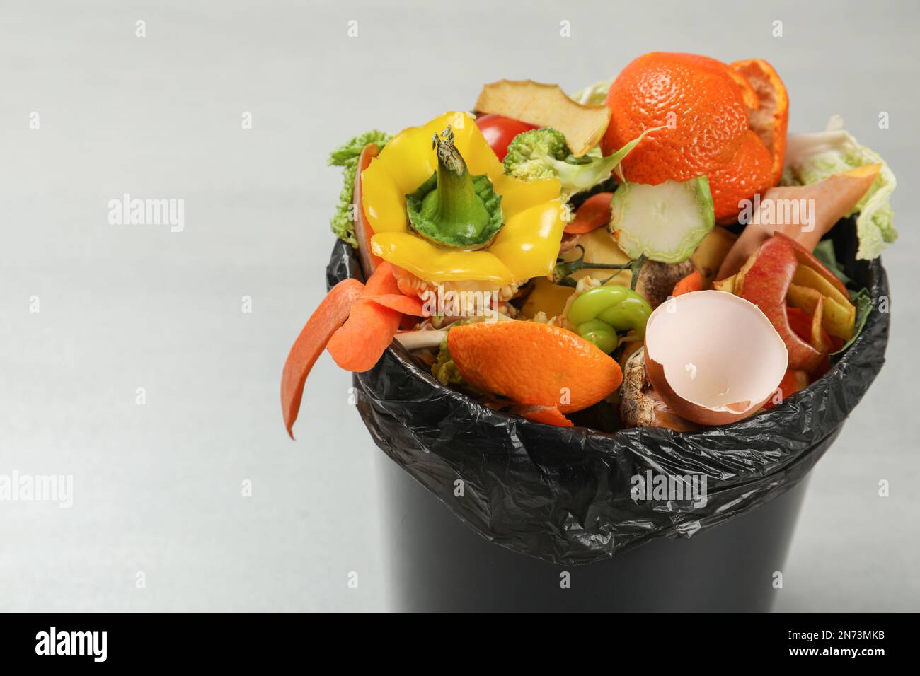 Trash bin with organic waste for composting on light background ...