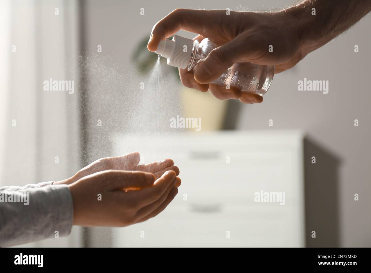Man spraying antiseptic onto child's hands indoors, closeup Stock Photo ...