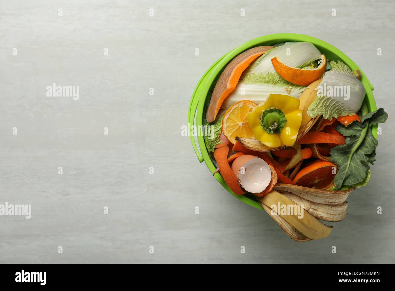 Natural garbage in trash bin on light background, top view with space ...