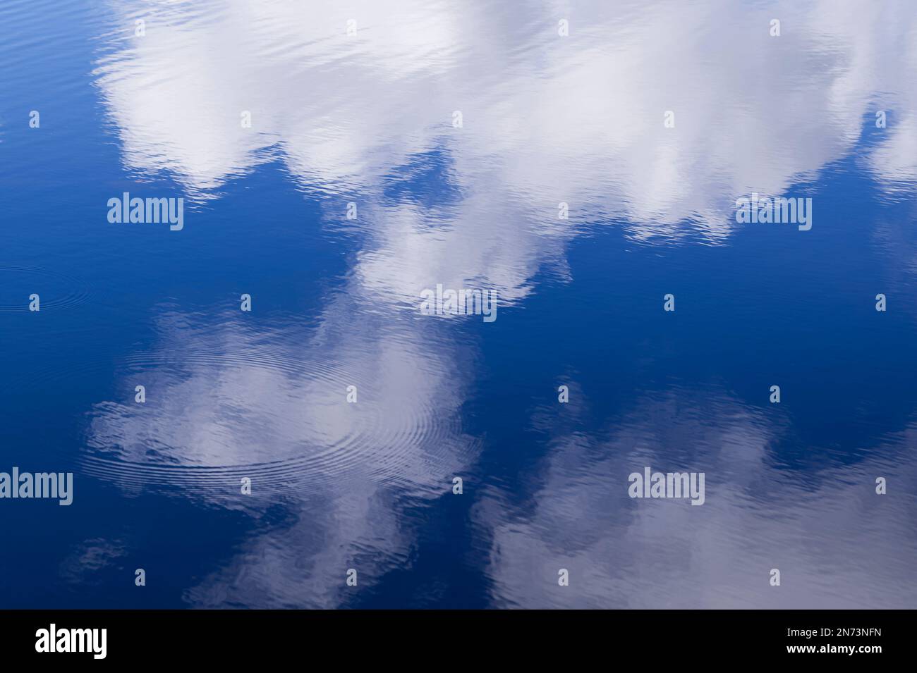 blue sky and white clouds reflected in the water of a lake, France ...