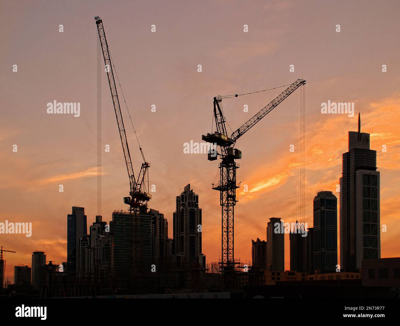 Sunset over skyline of cranes and buildings in Dubai City, United Arab ...