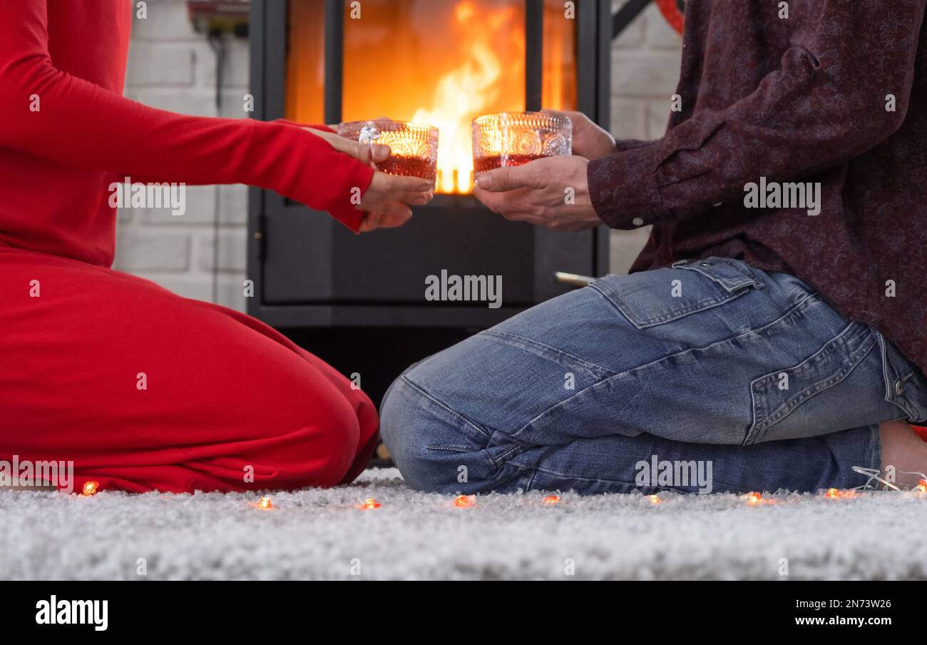 Man and woman in love date at home are sitting near the fireplace stove ...