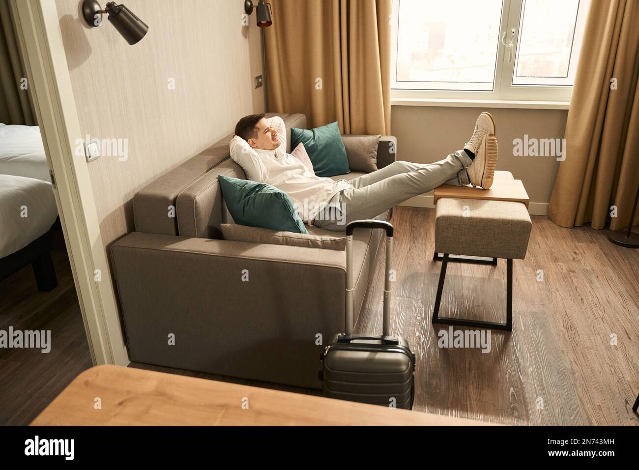 Man rests comfortably on a sofa in a hotel room Stock Photo - Alamy