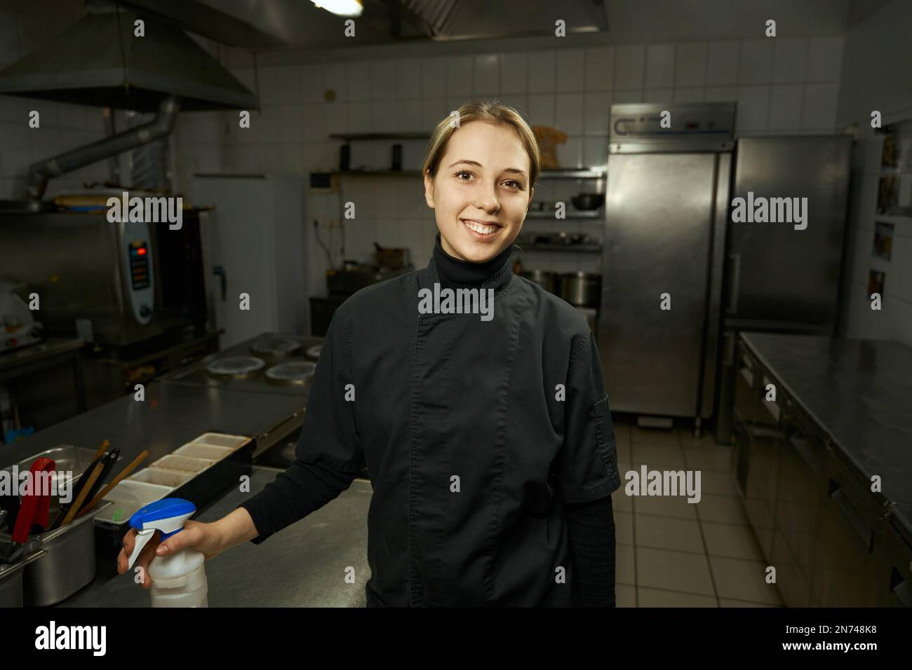 Smiling restaurant kitchen worker using disinfectant spray Stock Photo ...