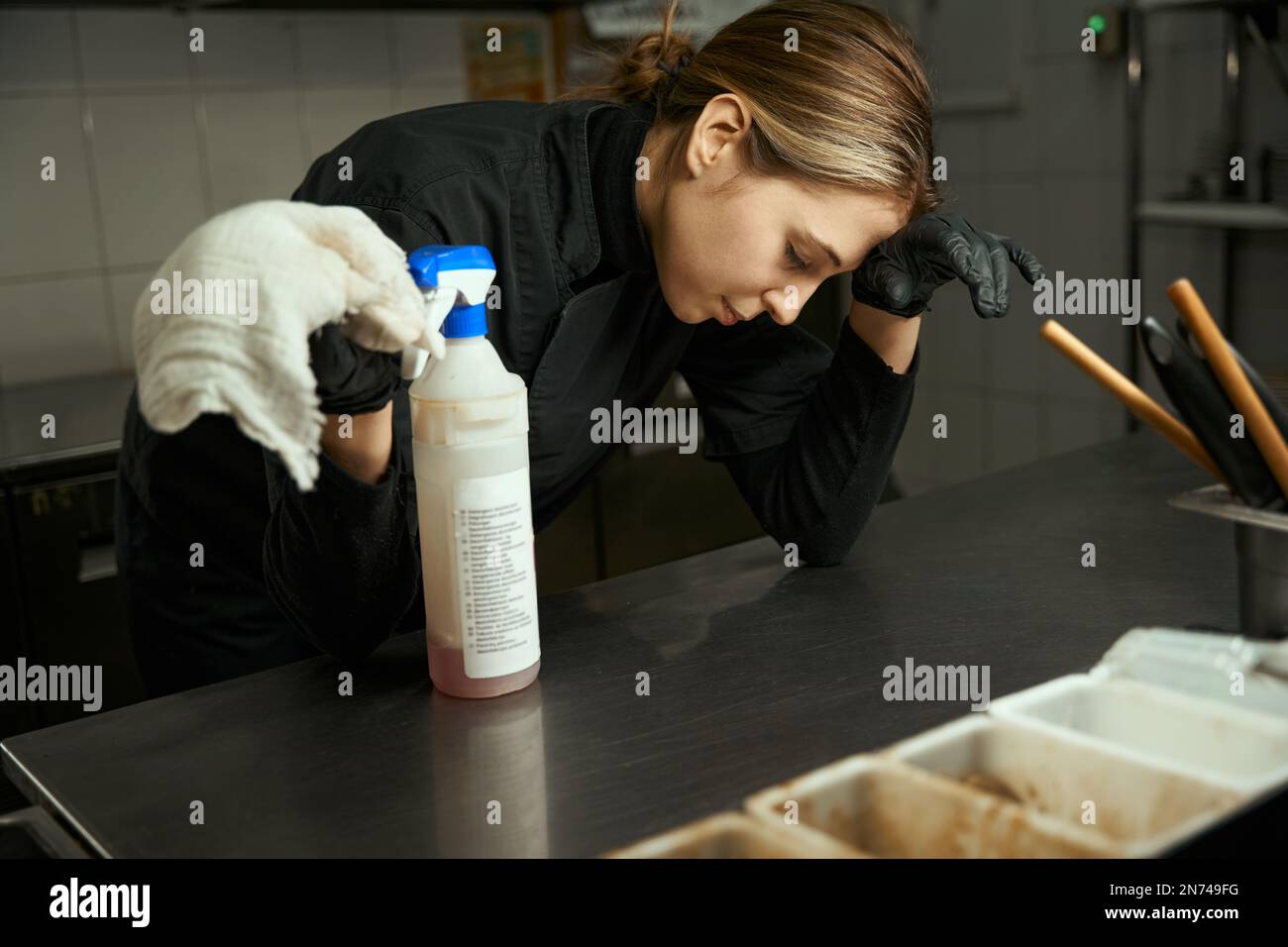 Kitchen worker is leaning over table and holding her head Stock Photo ...