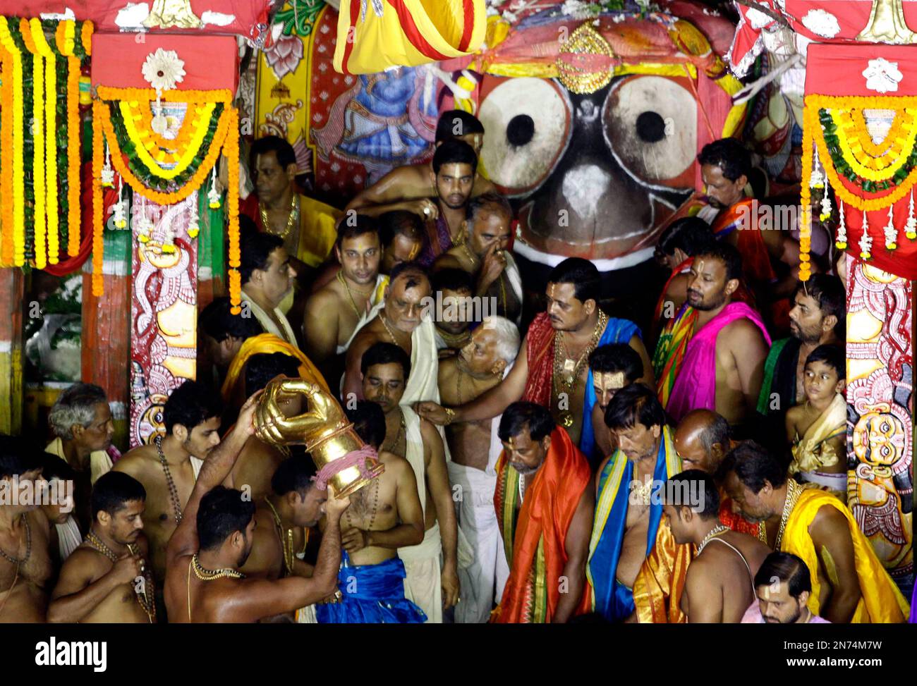 A temple worker carries a golden hand to dress up an idol of Hindu God ...