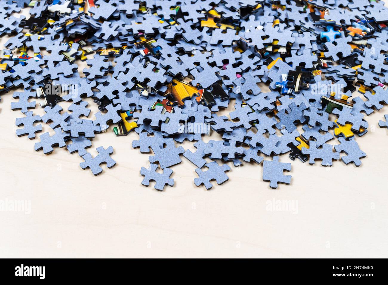 pile of puzzle pieces close up on light brown wooden table Stock Photo ...