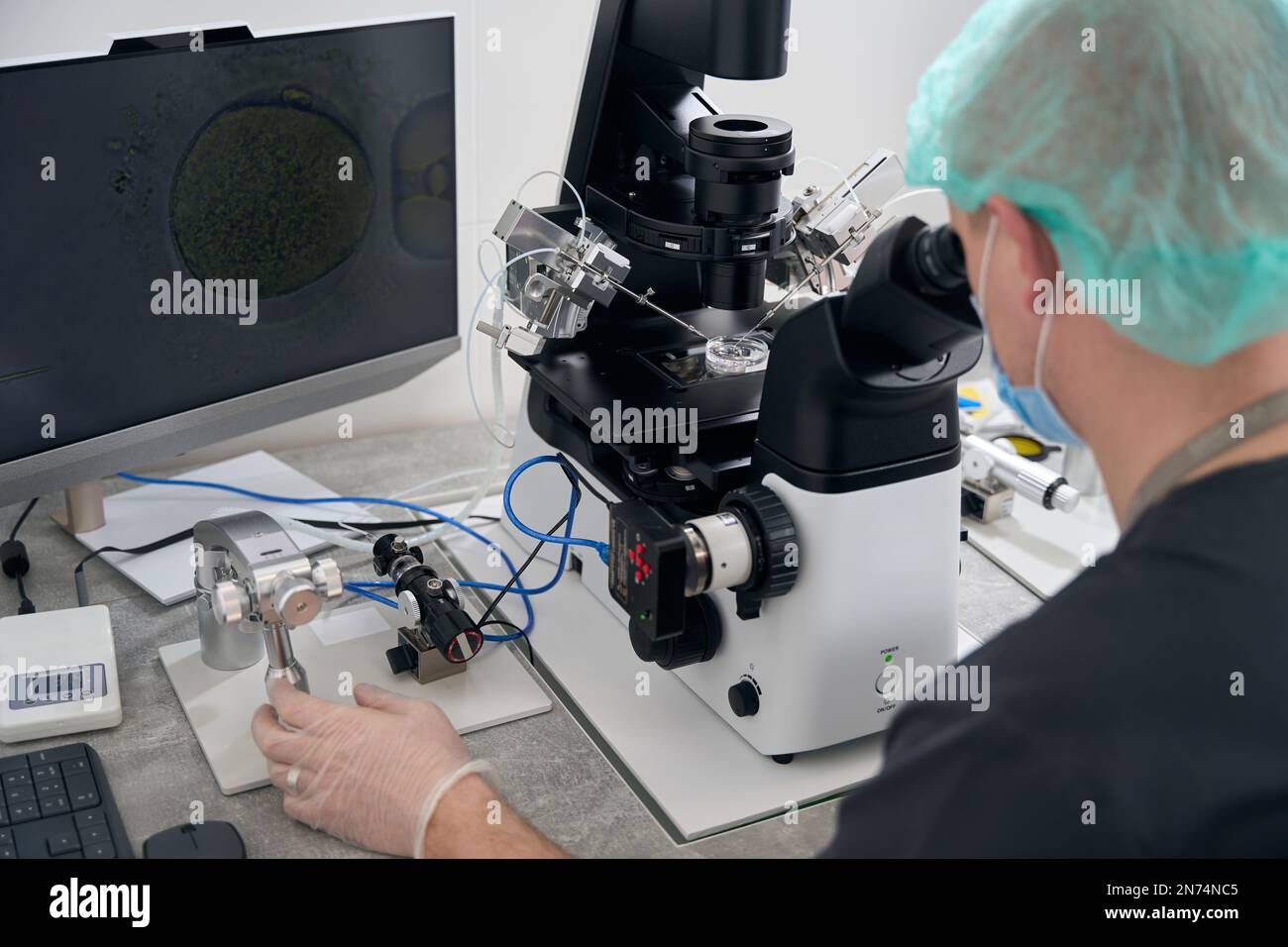 Doctor embryologist worksbehind a powerful microscope with a ...