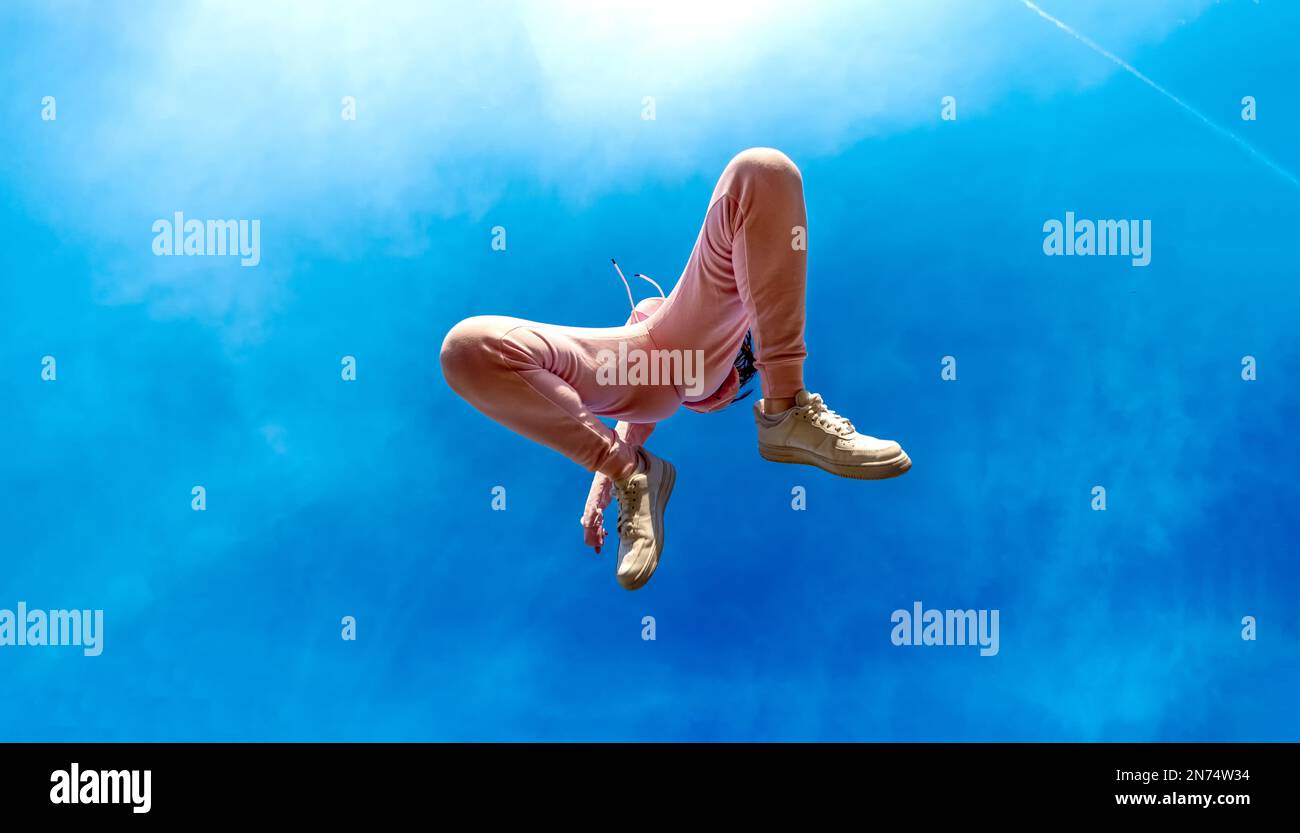 view from below to young beautiful woman in pink sports suit jumps full ...