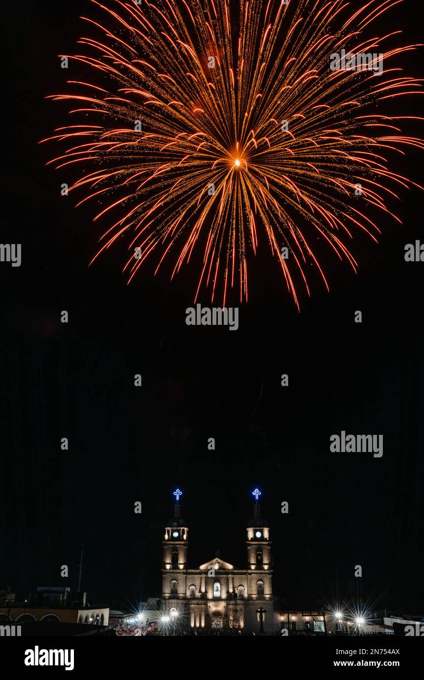 A Vertical shot of fireworks in front of church during city's holidays ...