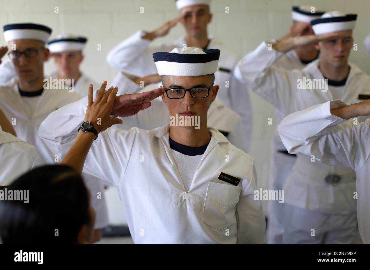 A midshipman adjusts a prospective plebe's salute as he stands in ...