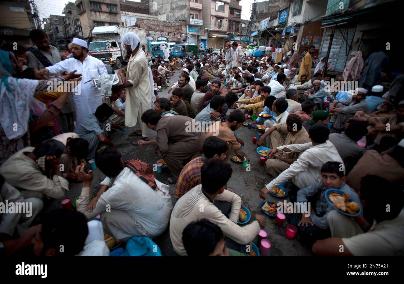 Pakistani poor people wait for iftar to break the fast during the ...