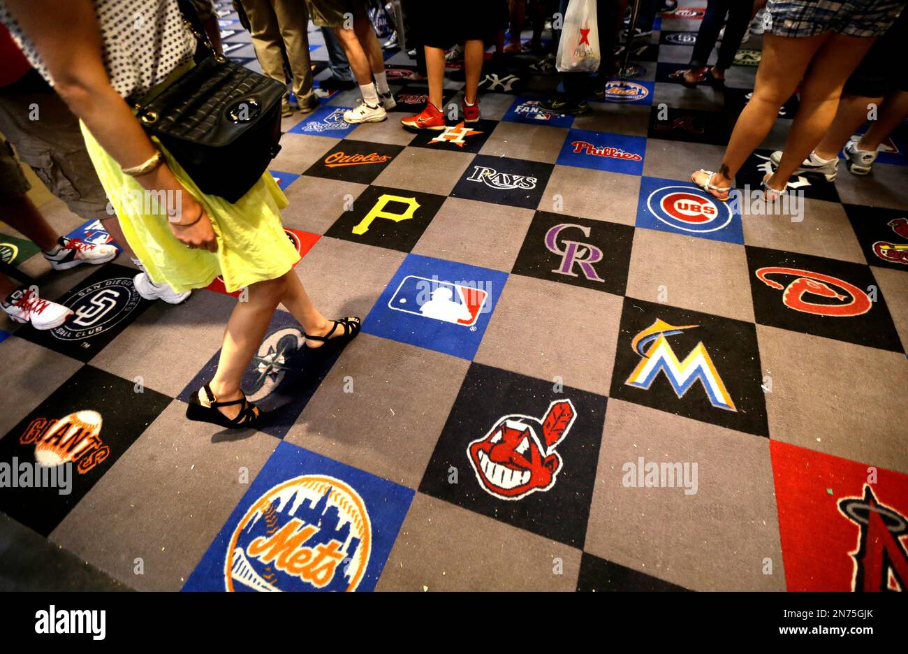 People walk on a rug featuring baseball team logos during Major League ...