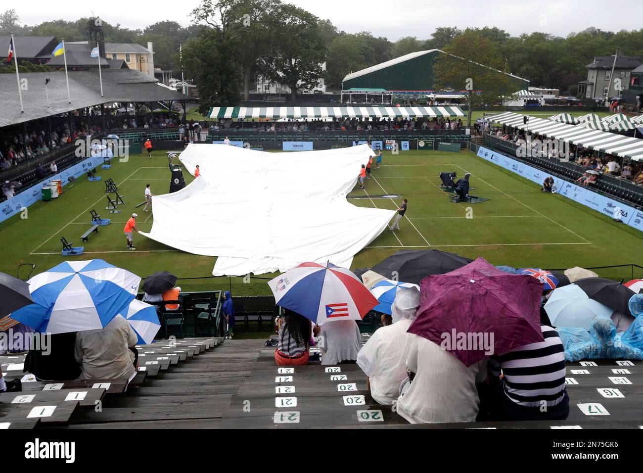 Fans in the south stands shelter under umbrellas as they watch a tarp ...