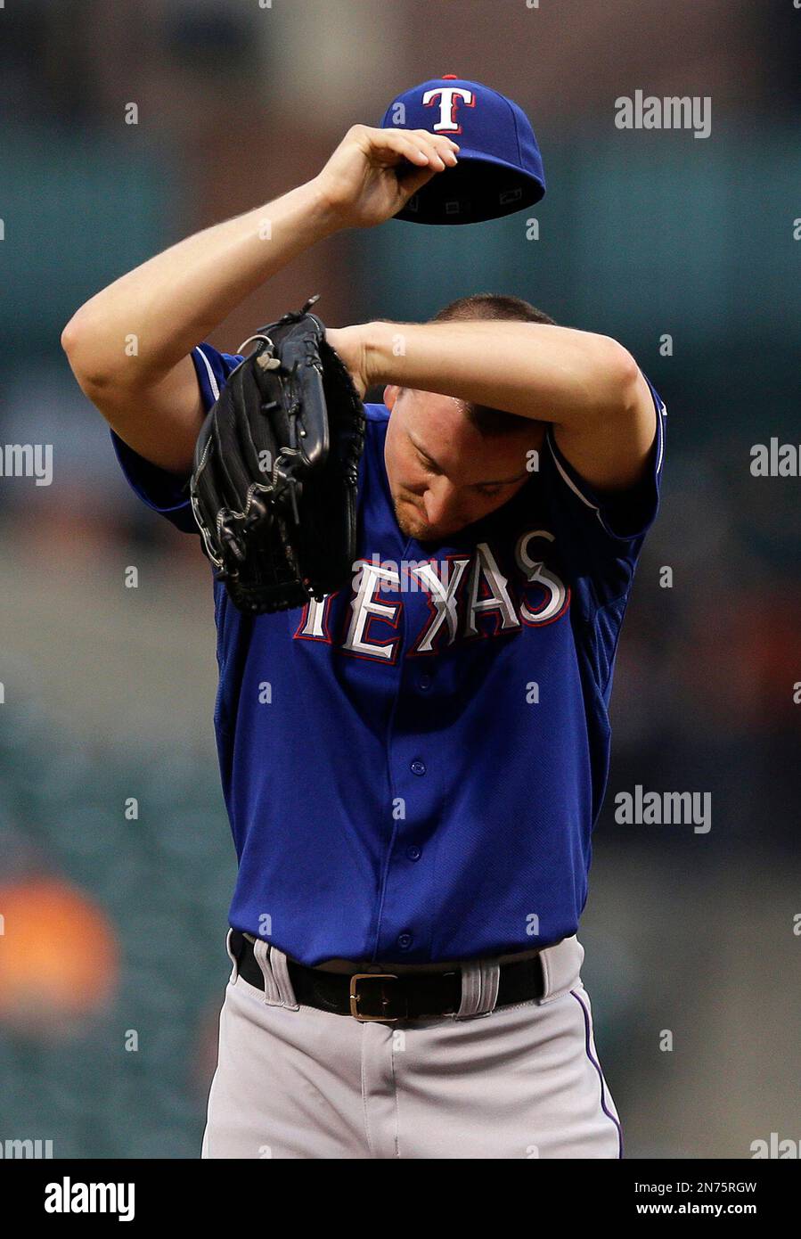 Texas Rangers starting pitcher Ross Wolf wipes sweat from his forehead ...