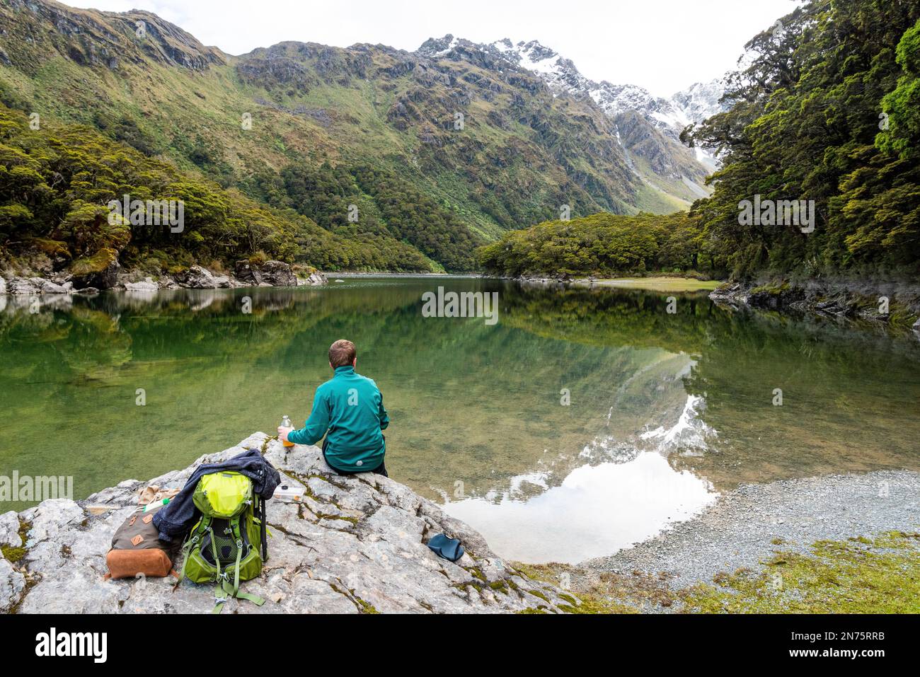 Hiker resting at mountain lake Mackenzie at the famous Routeburn Track ...