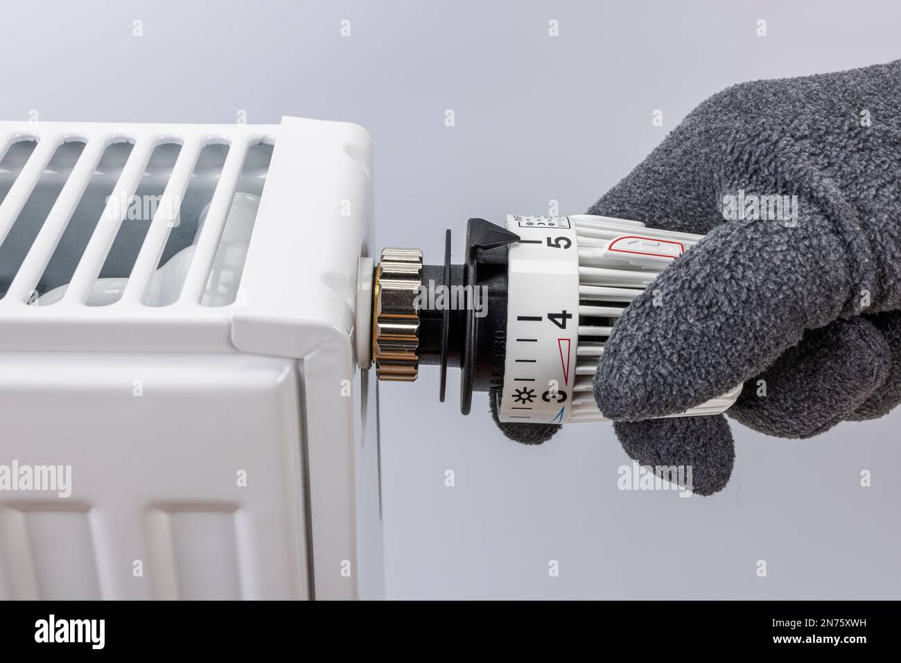 Man hand with glove increases room temperature on radiator thermostat ...