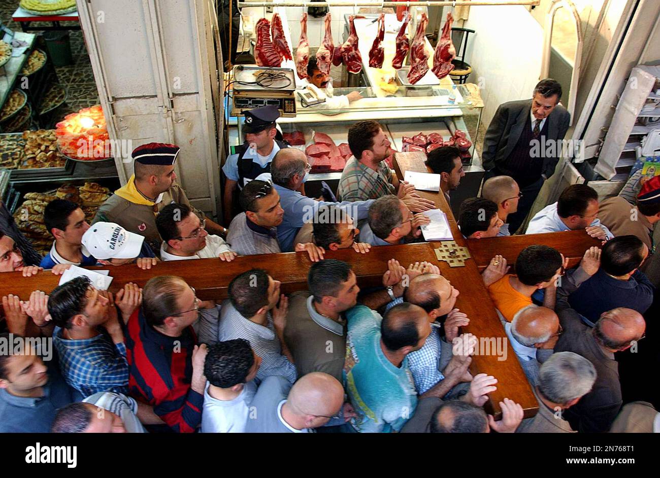 An Arab butcher looks on as Christian worshippers carry a cross along ...
