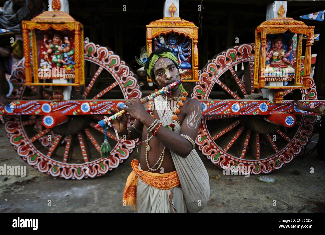 A devotee dressed as Lord Krishna plays the flute ahead of the annual ...