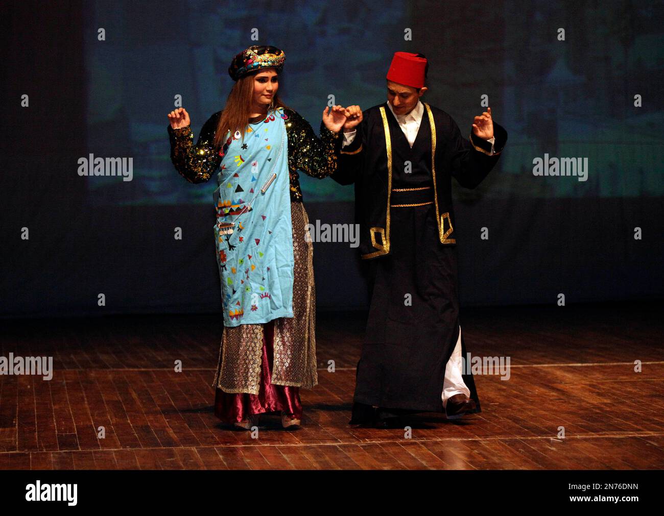 Dancers wearing traditional Iraqi folk costumes perform during a ...