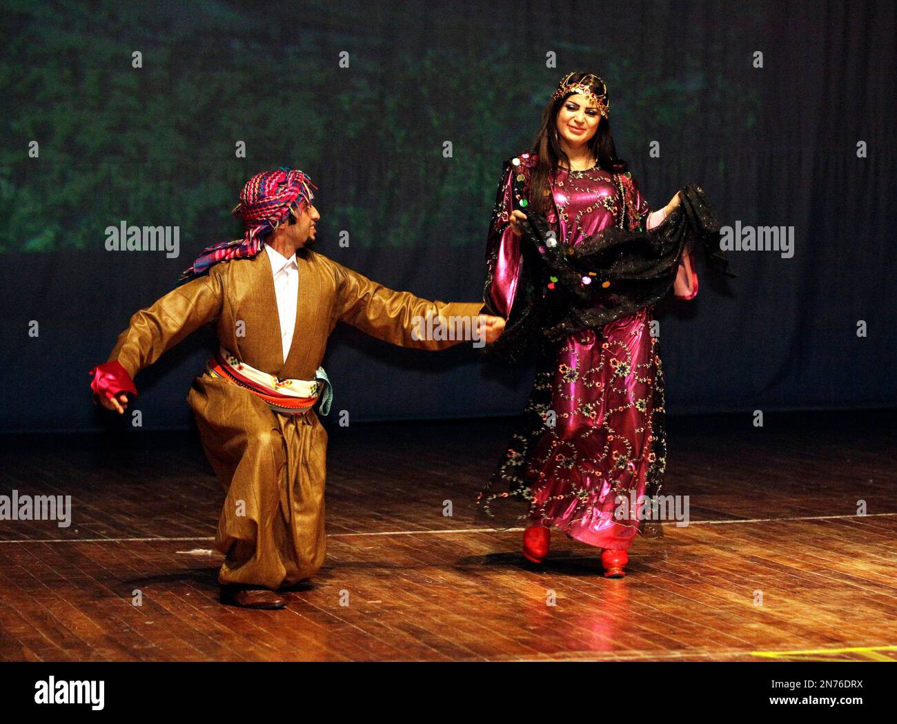 Dancers wearing traditional Iraqi folk costumes perform during a ...