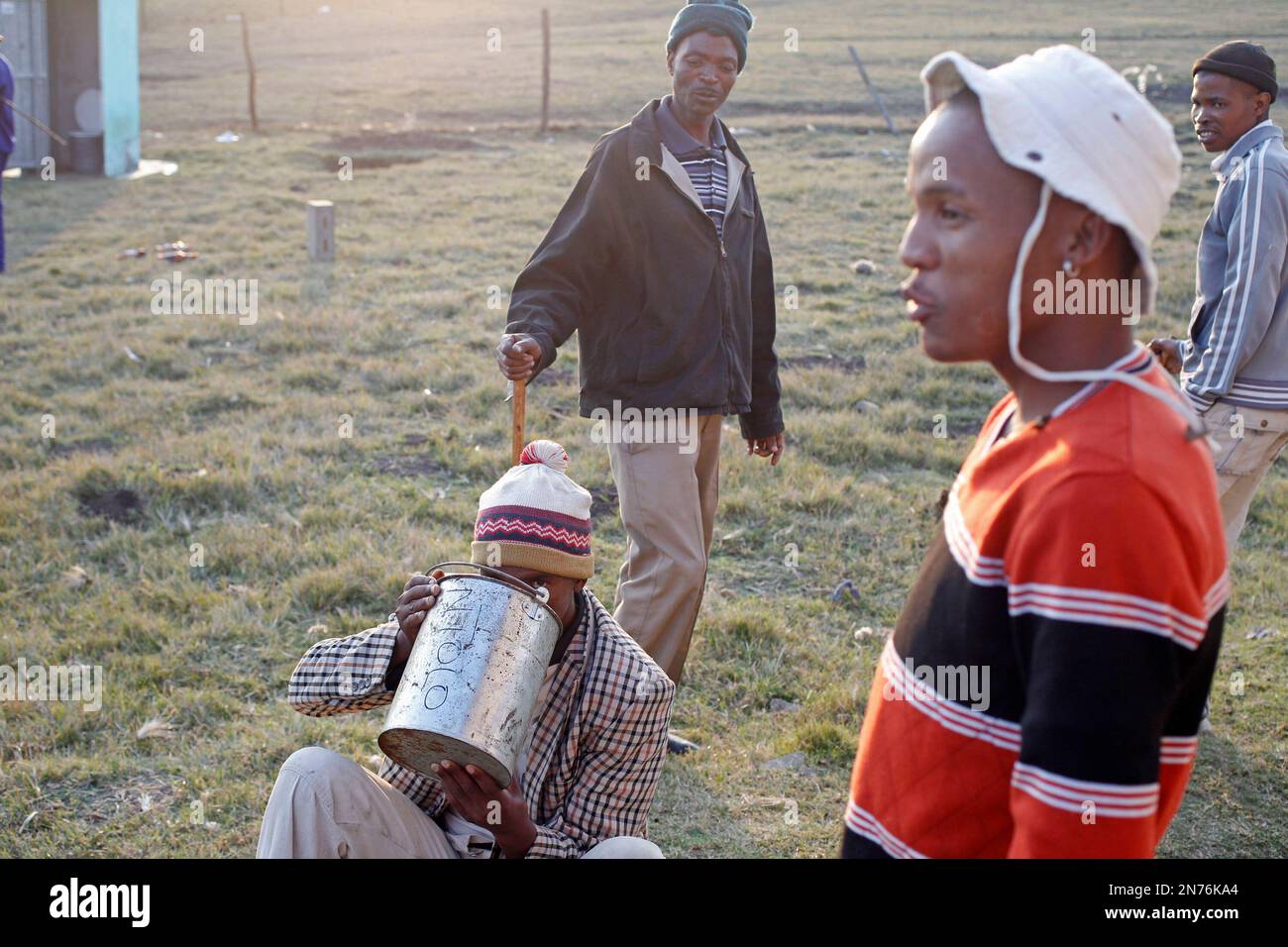 A man drinks traditional beer out of a tin can as they celebrate a ...