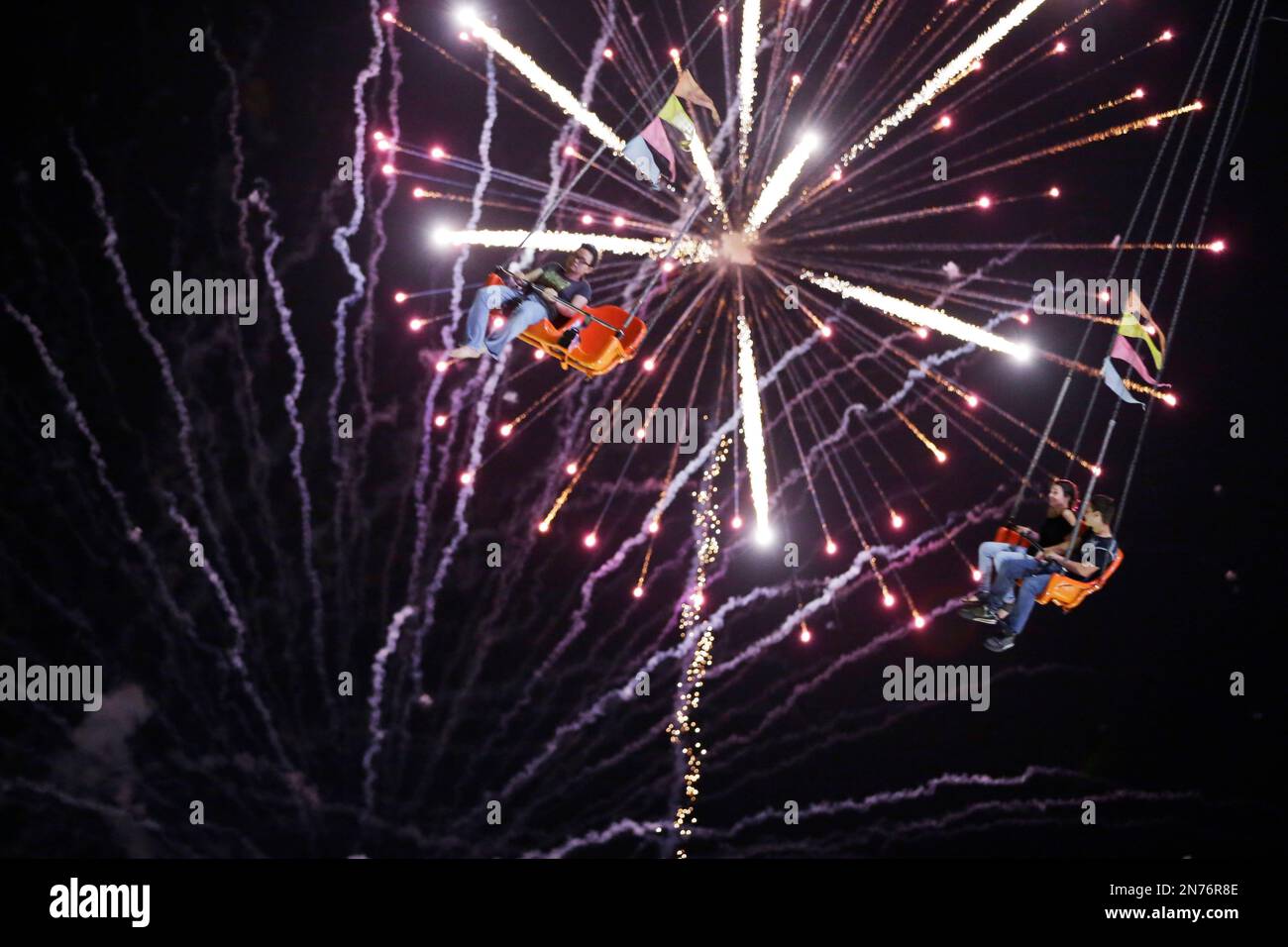 Fireworks explode as people ride the Sky Flyer carnival ride at State ...