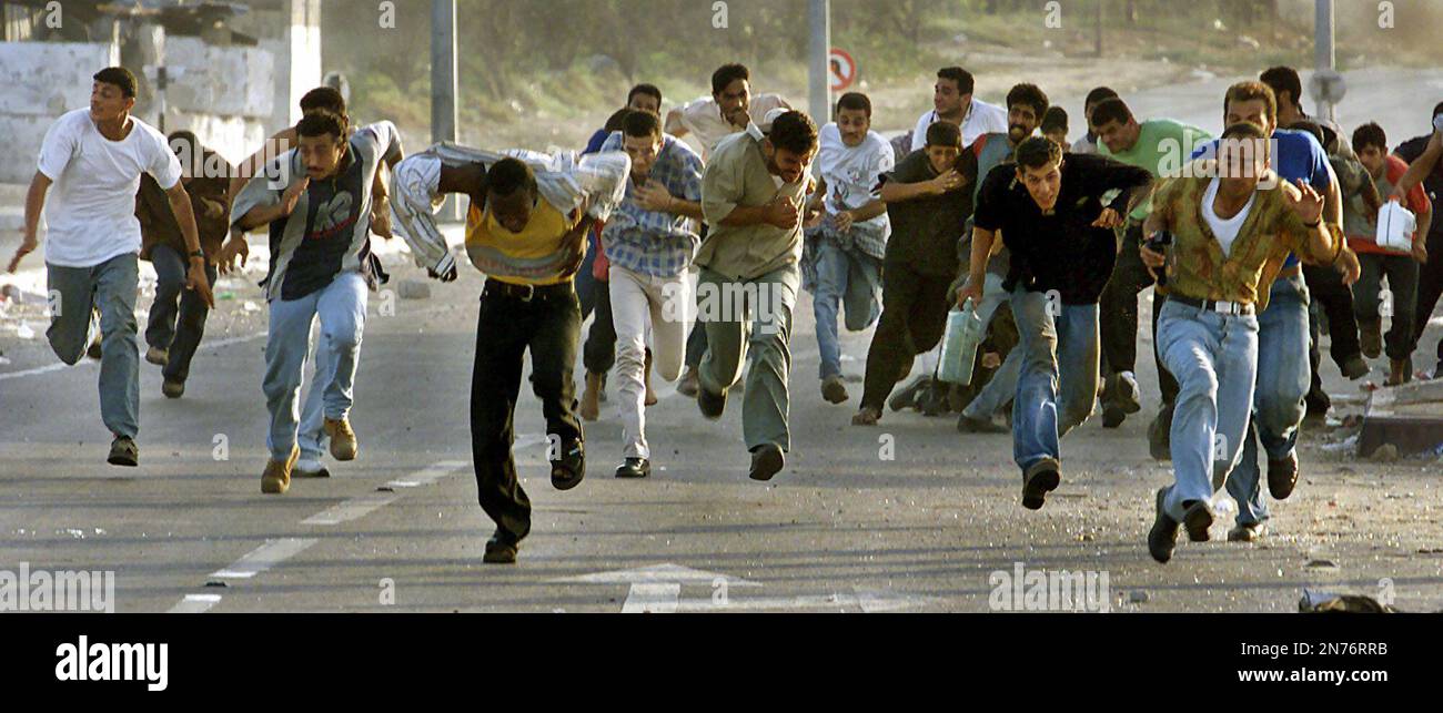 Palestinians run for cover as a rocket fired from a Israeli Army ...