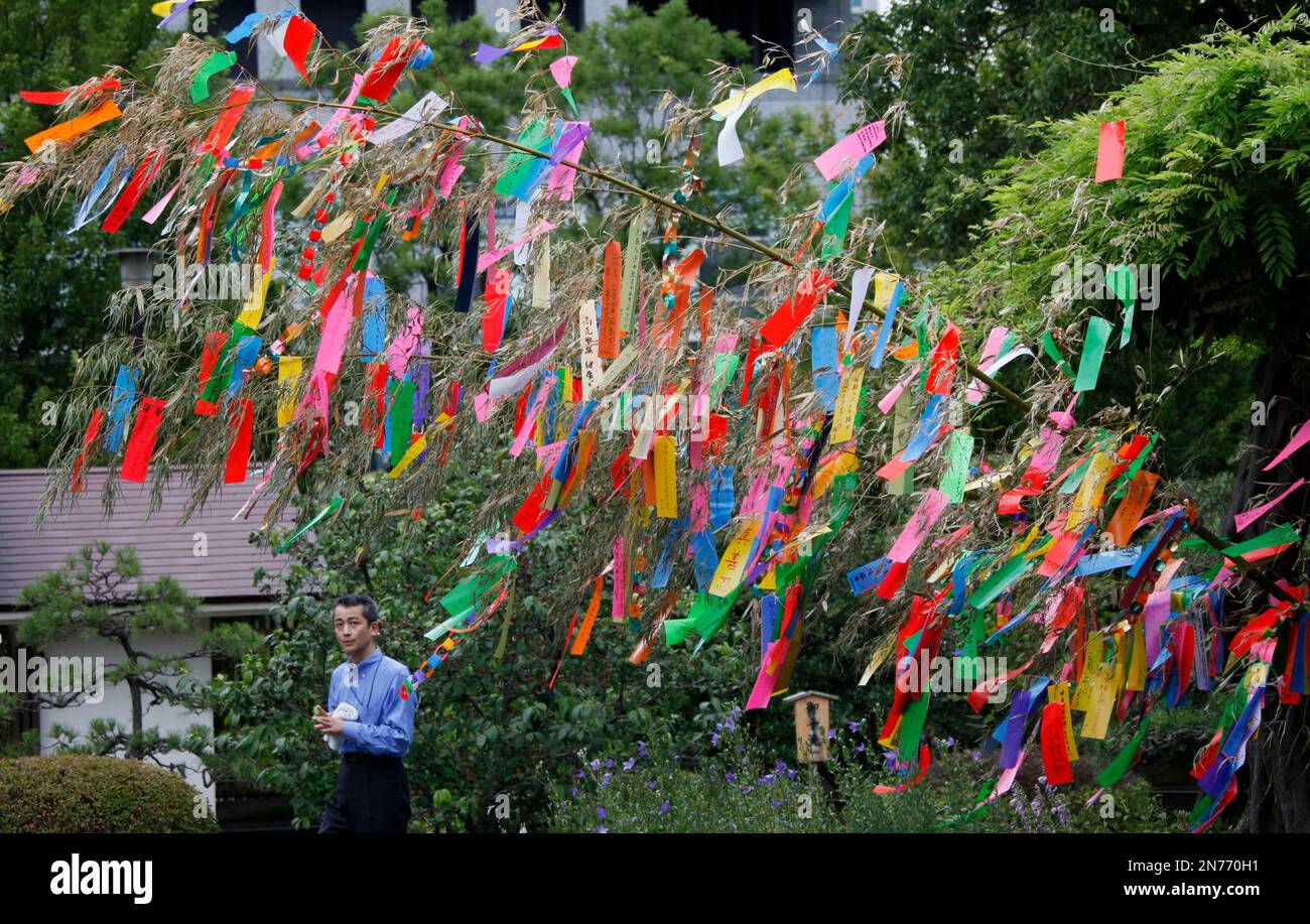 A man walks by a bamboo tree decorated with colorful strips of paper at ...