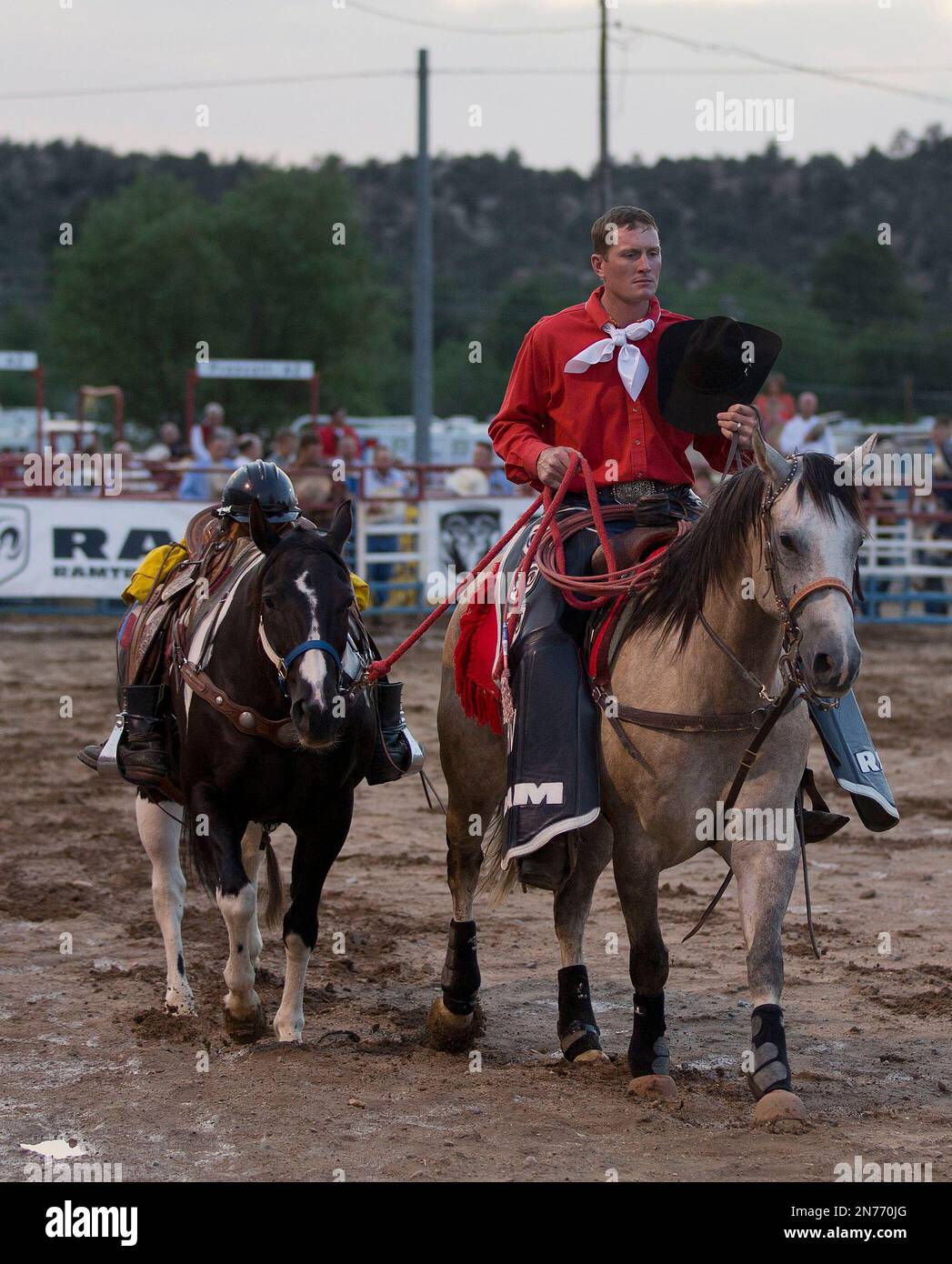 A rodeo outrider leads a riderless horse with a firefighter's helmet ...